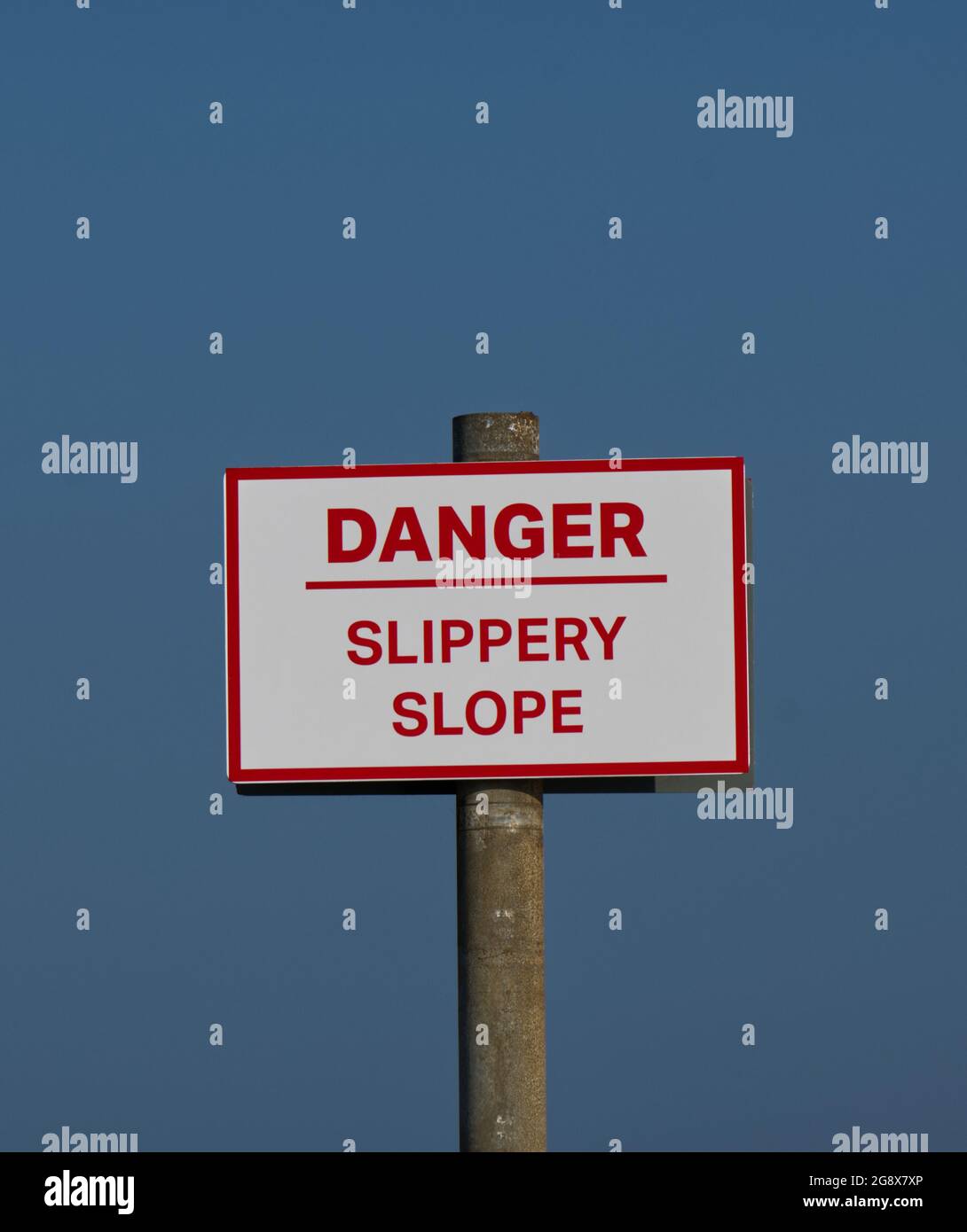 Rectangular red and white danger slippery slope warning sign against hi ...