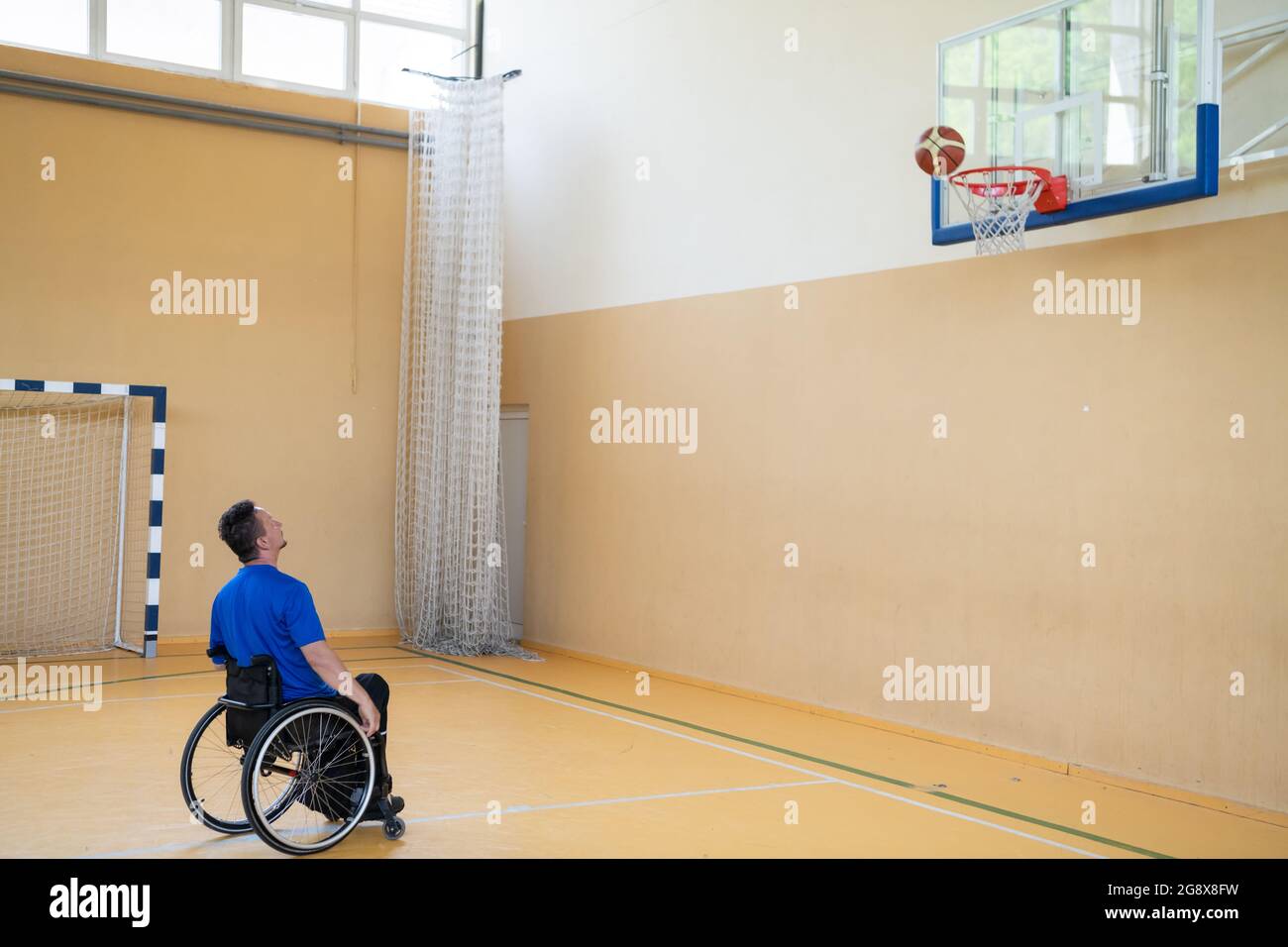 a war invalid in a wheelchair trains with a ball at a basketball club ...