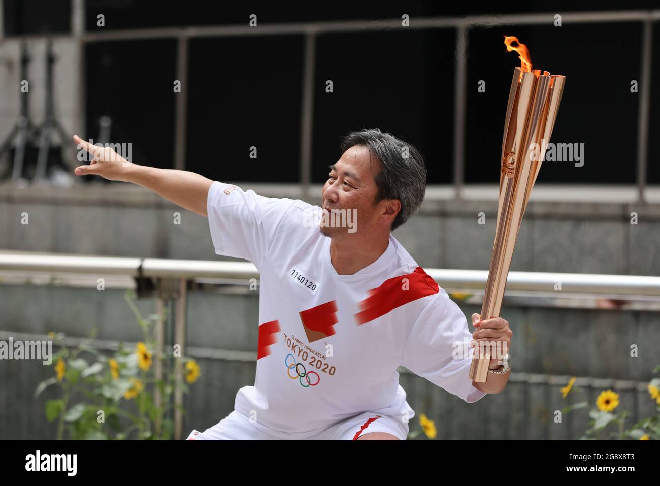 Tokyo, Japan. 23rd July, 2021. A torchbearer poses for a photo with the ...