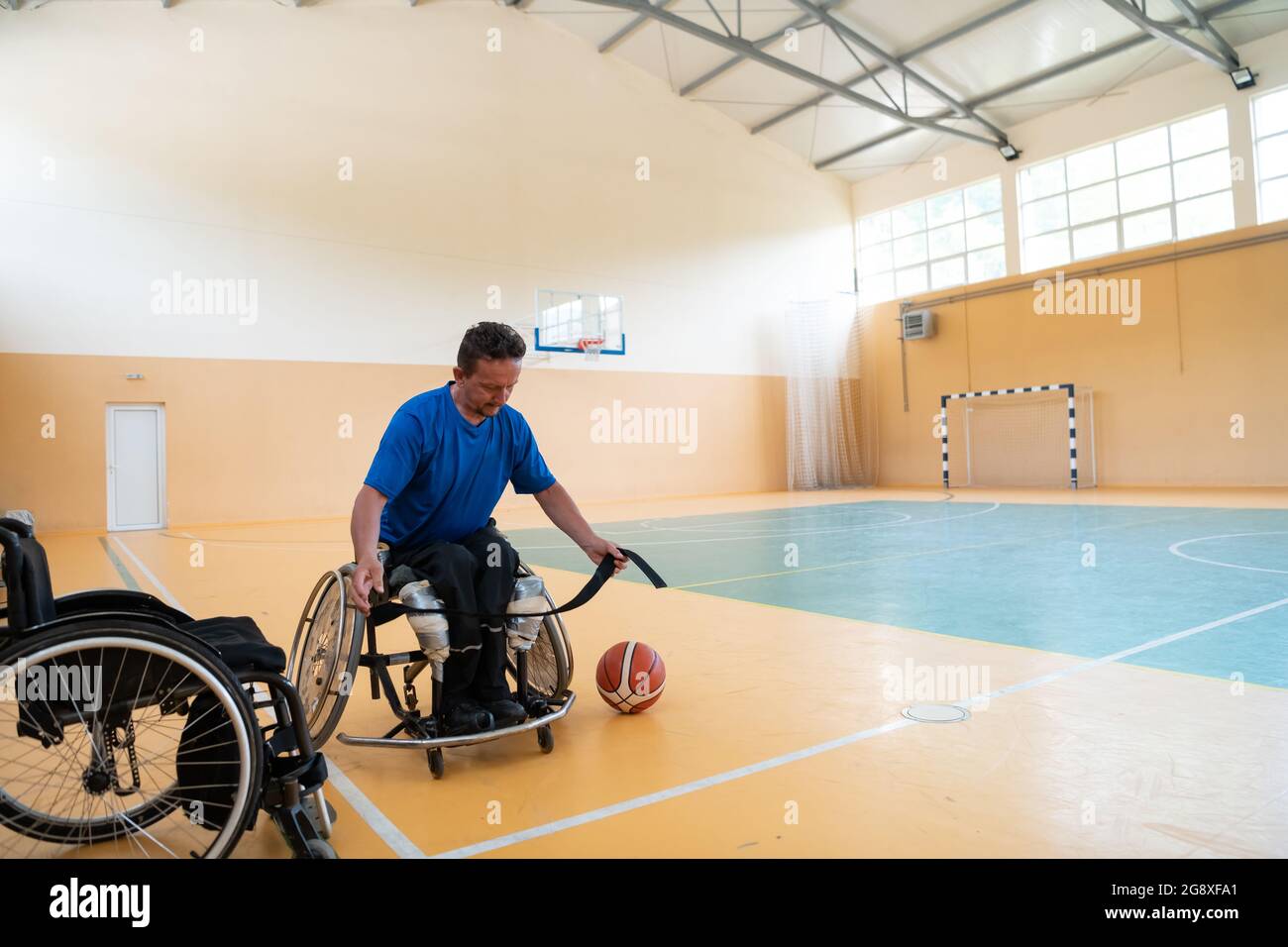 a handicapped basketball player prepares for a match while sitting in a ...