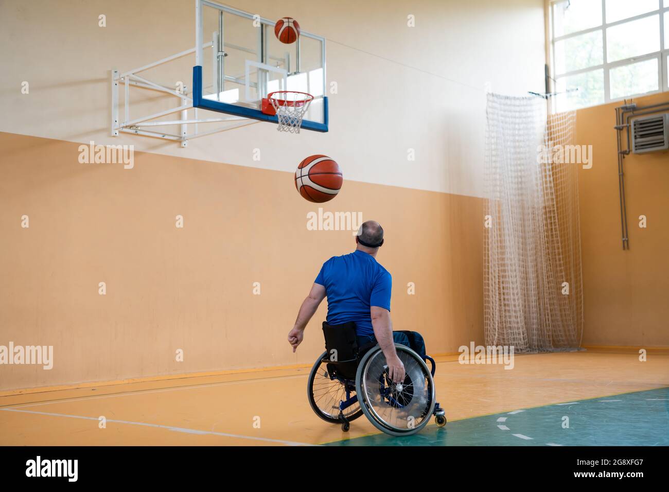 a war invalid in a wheelchair trains with a ball at a basketball club ...