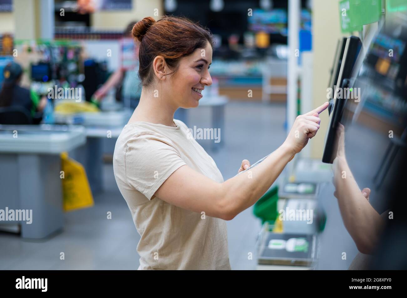 Caucasian woman uses a self-checkout counter. Self-purchase of ...