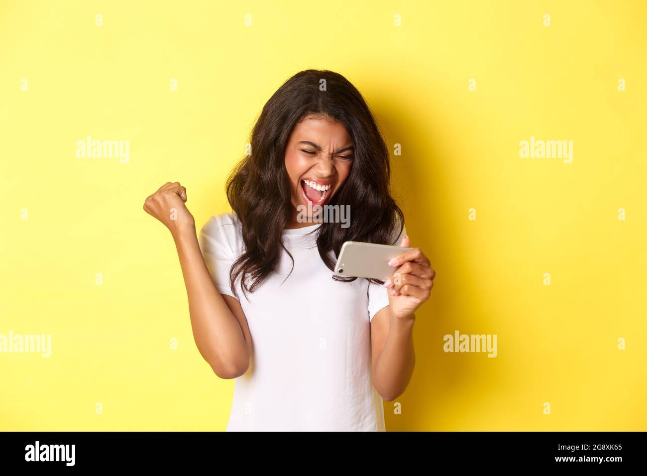 Portrait of cute african-american girl winning in smartphone game ...