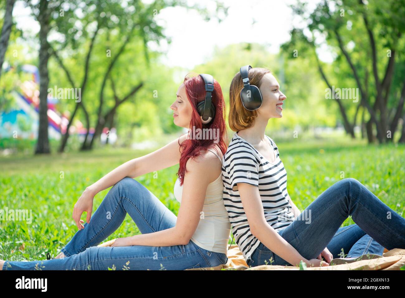 Two young girls in the park listen to music Stock Photo - Alamy