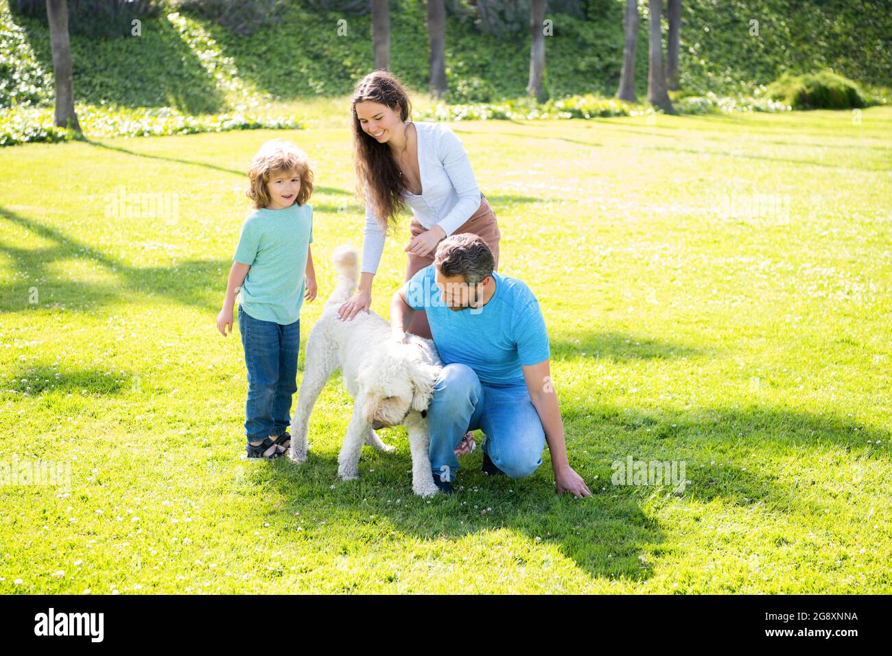 happy family of mother daddy and kid son playing with pet dog in summer ...