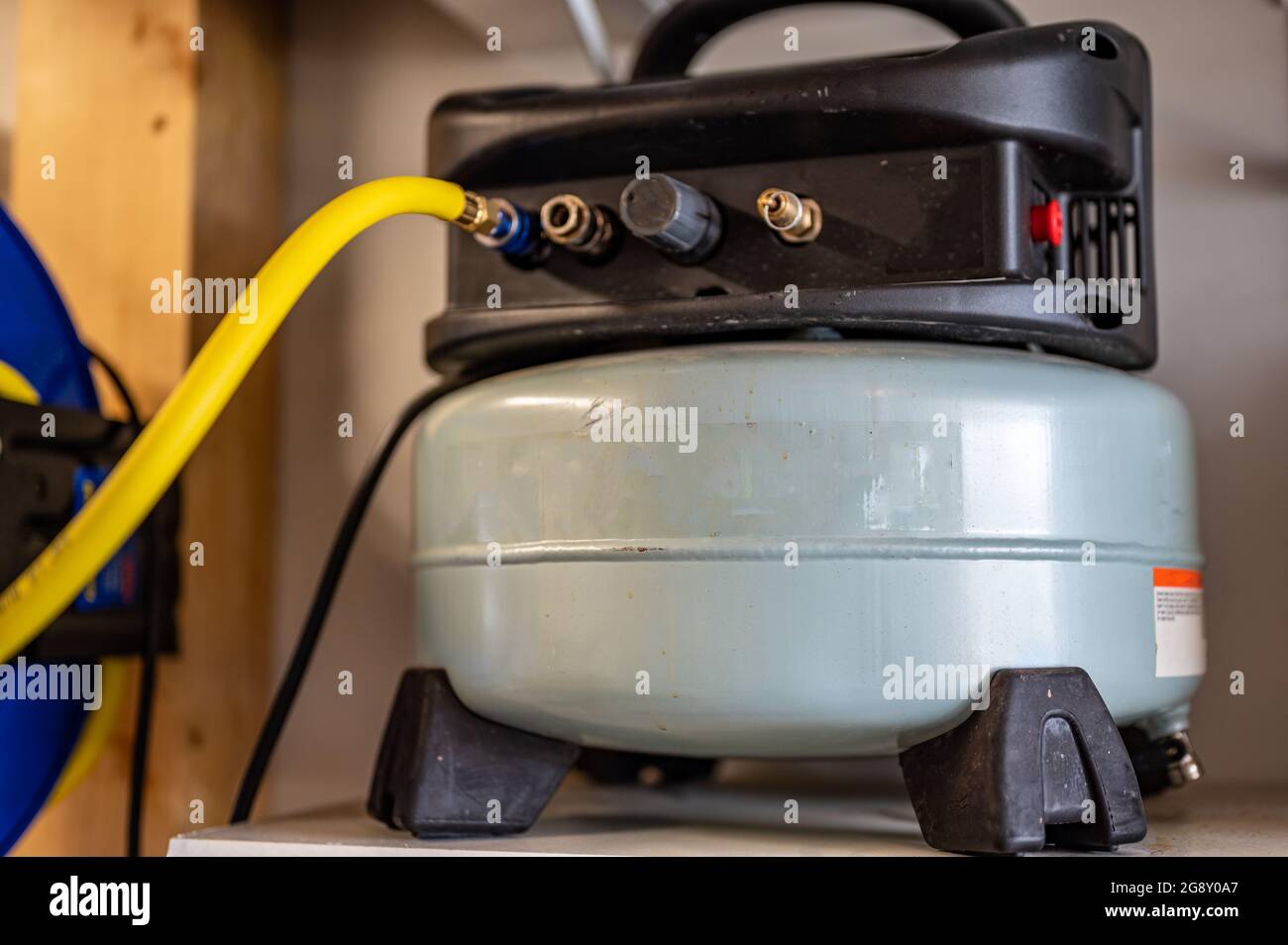 Pancake air compressor sitting on a shelf with a hose connected Stock ...