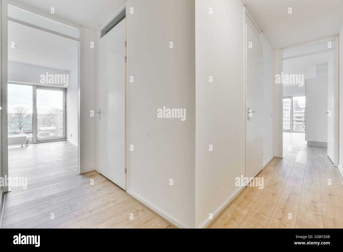 Corridor separating two rooms. Rooms with white walls and wooden floors ...