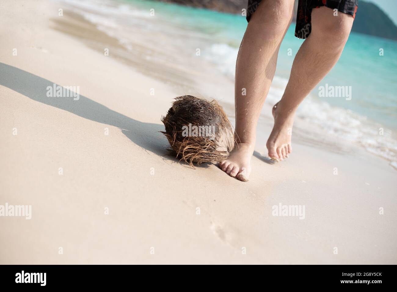 male feet barefoot on white sand by the sea, next to a coconut Stock ...