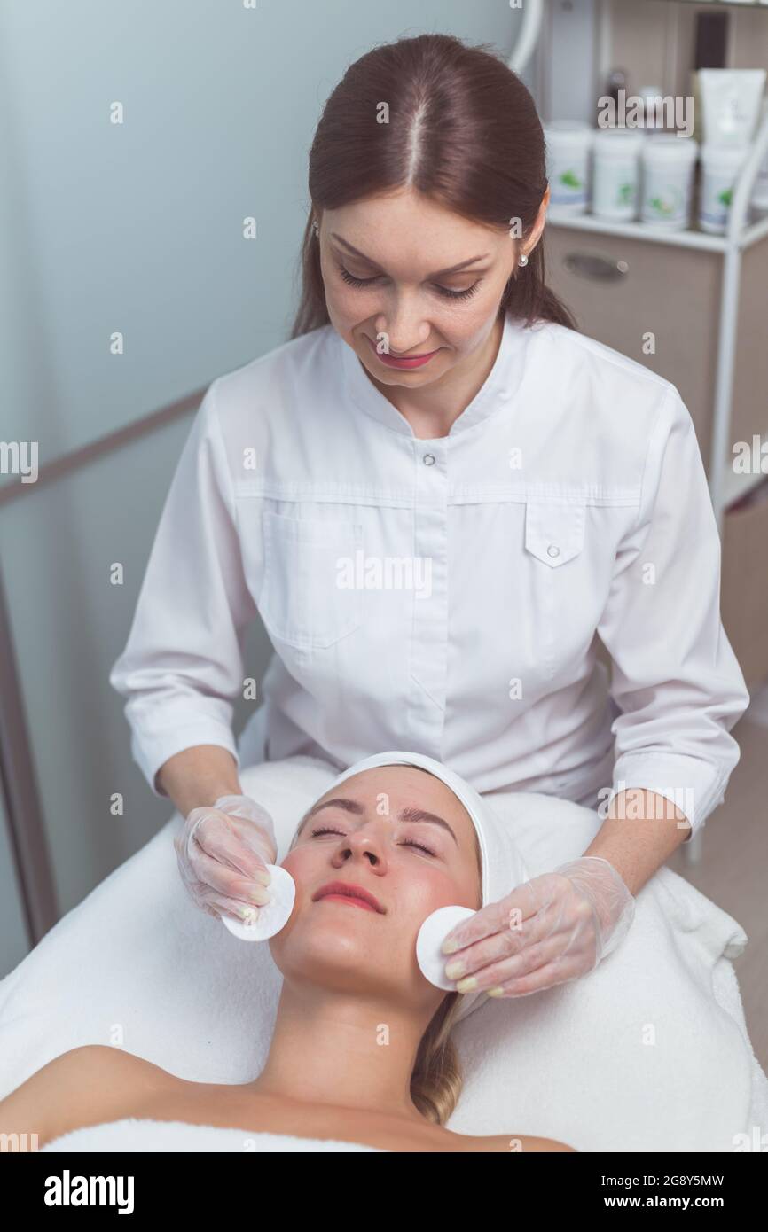 Doctor beautician cleanses face skin with sponge in beauty salon Stock ...