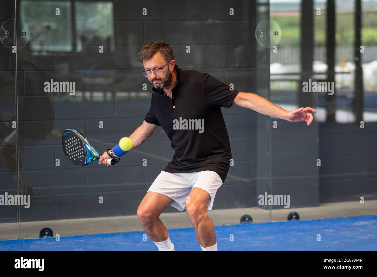 Man playing padel in a blue grass padel court indoor - Young sporty boy ...