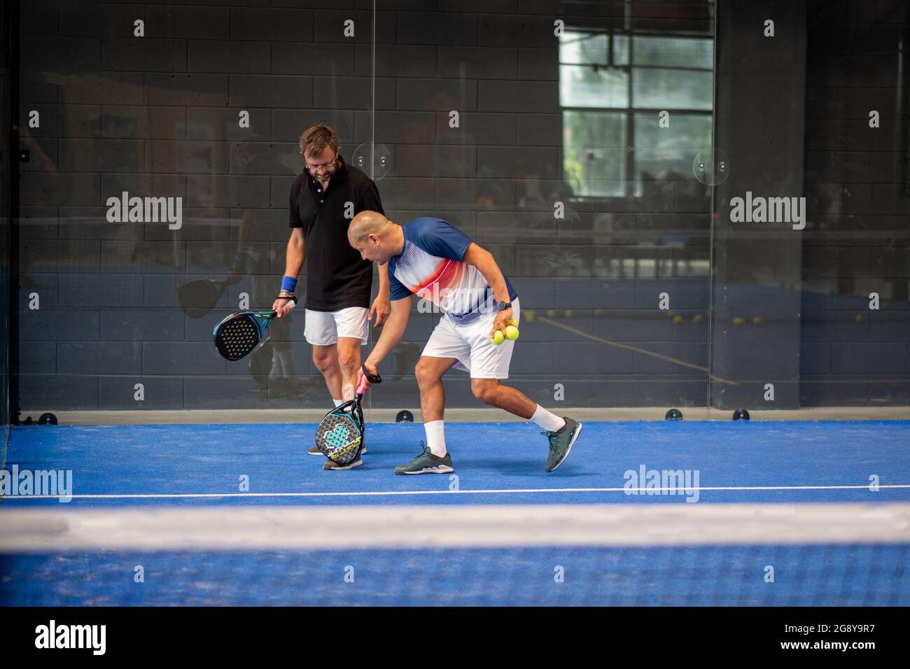 Monitor teaching padel class to man, his student - Trainer teaches boy ...