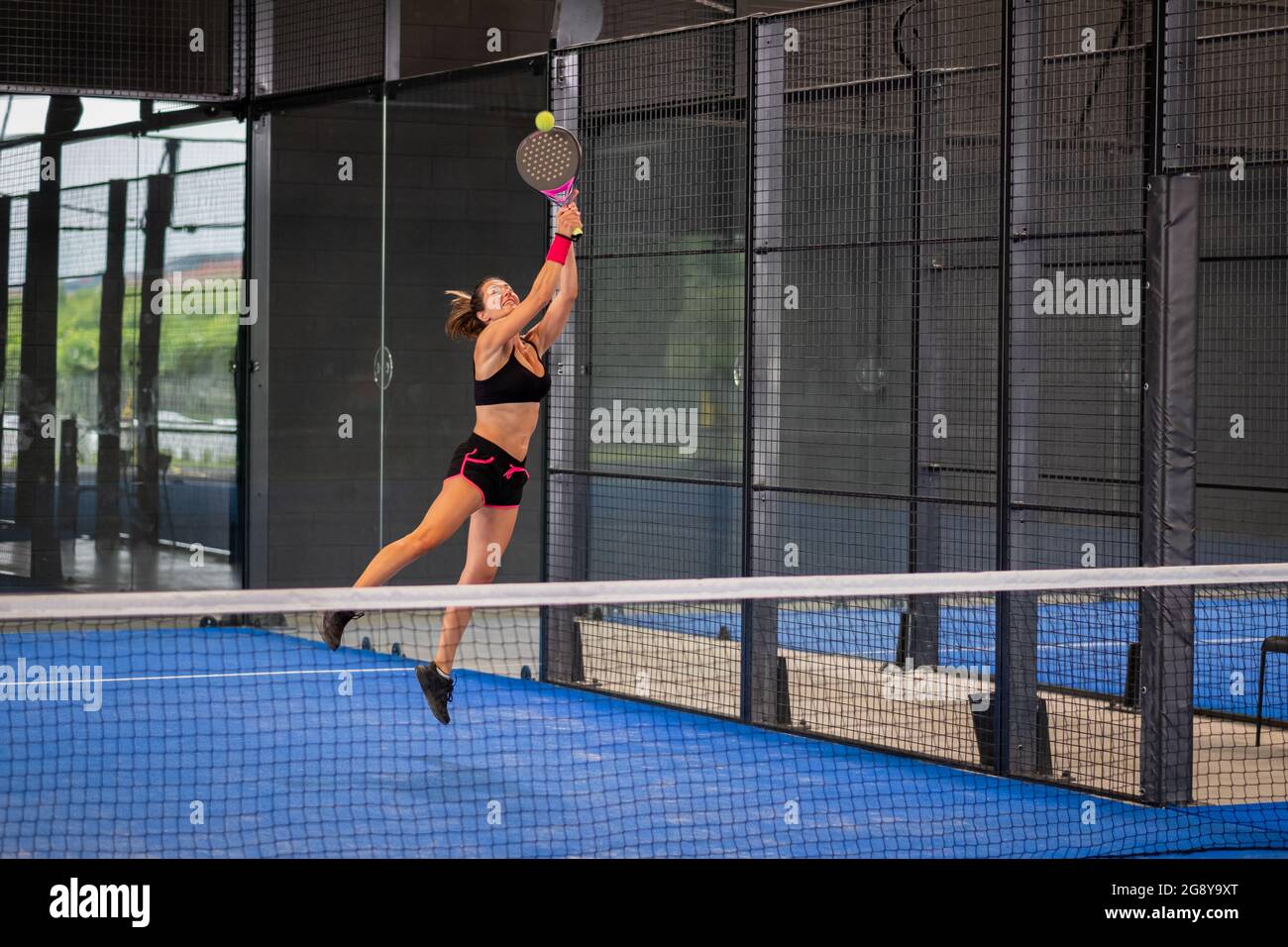 Woman playing padel in a blue grass padel court indoor - Young sporty ...