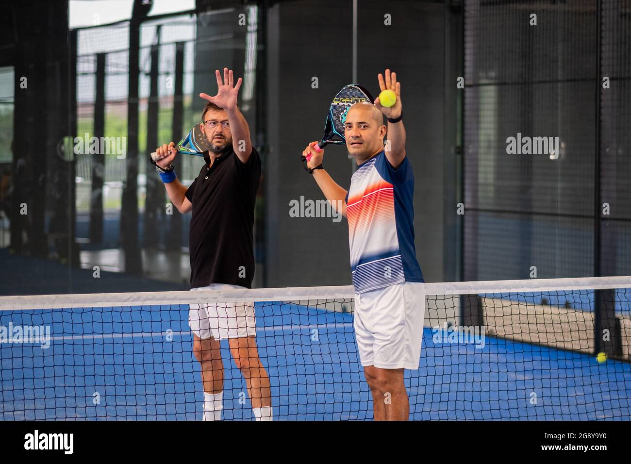 Monitor teaching padel class to man, his student - Trainer teaches boy ...