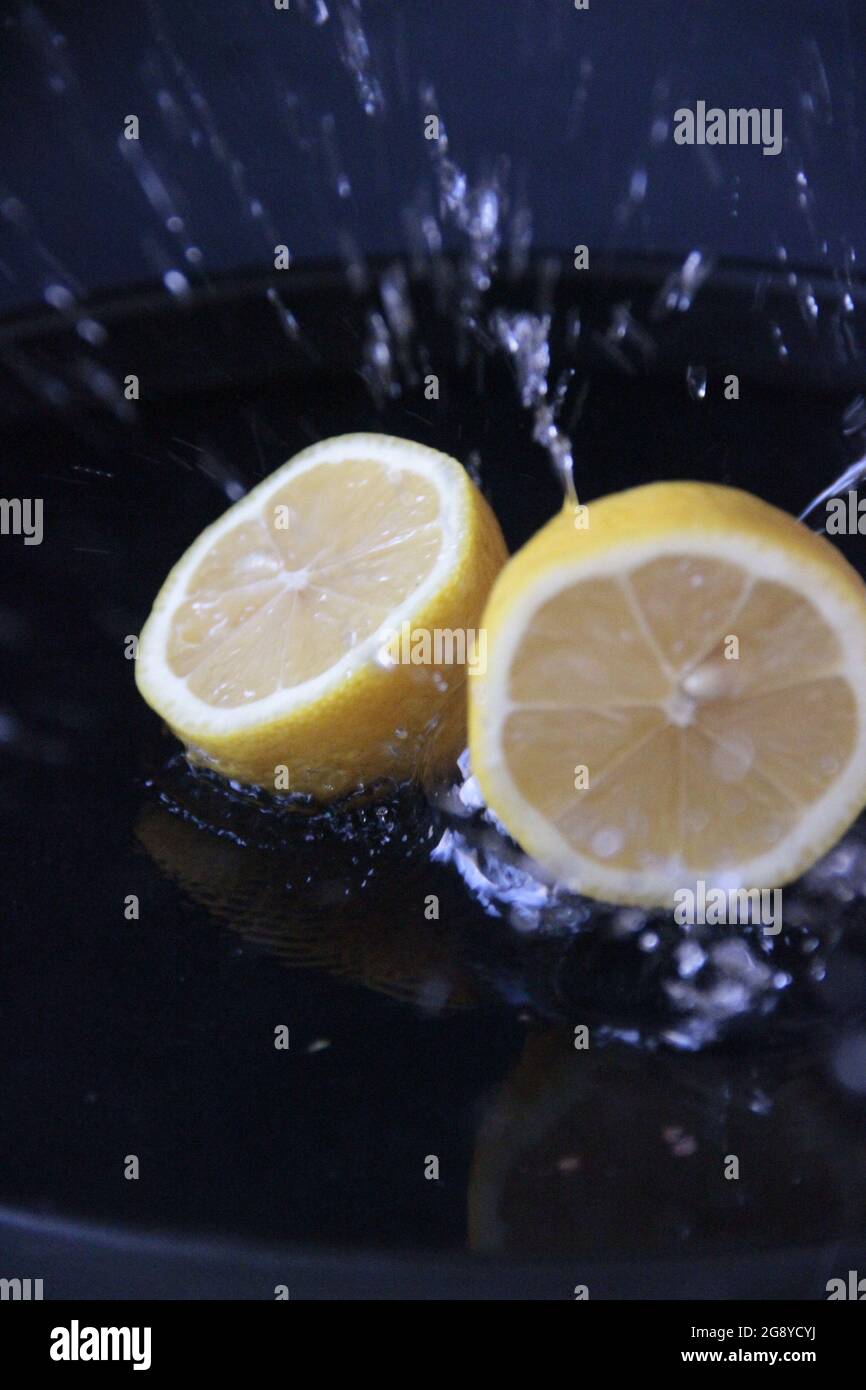 Lemons splashing into water on dark background Stock Photo - Alamy