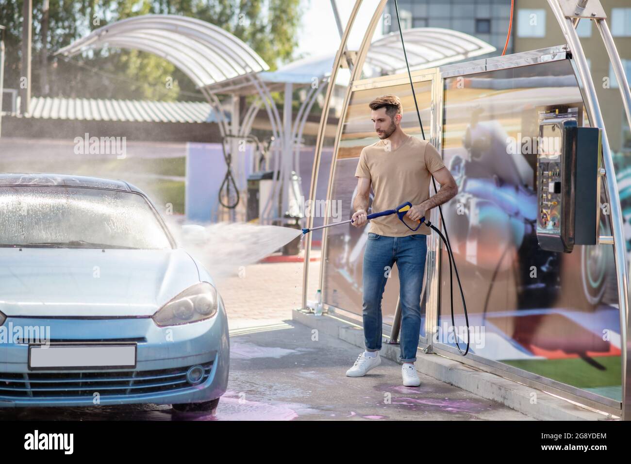 Attractive slim man washing car spraying water Stock Photo - Alamy