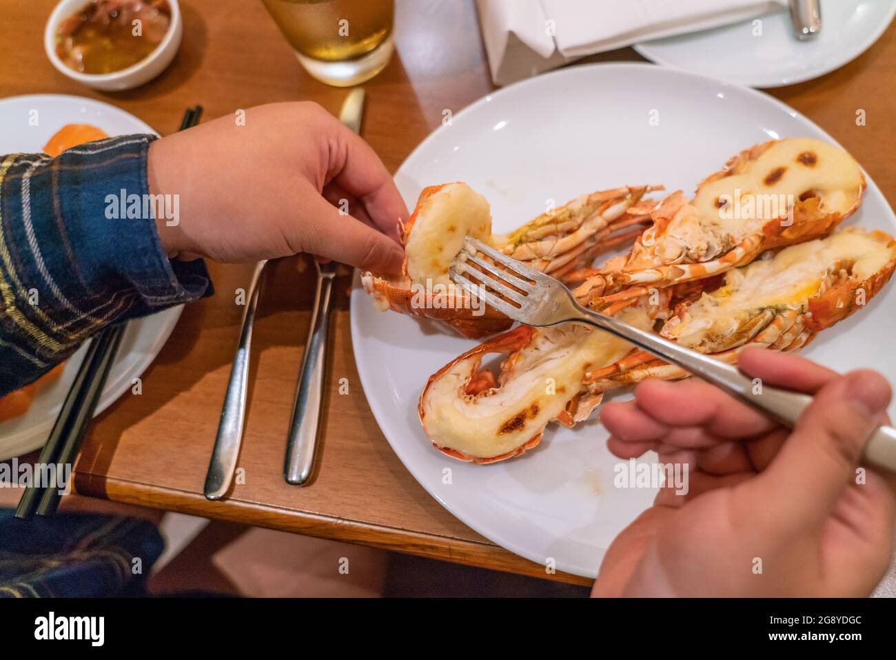 Woman hand eating Grilled Lobster Stock Photo - Alamy