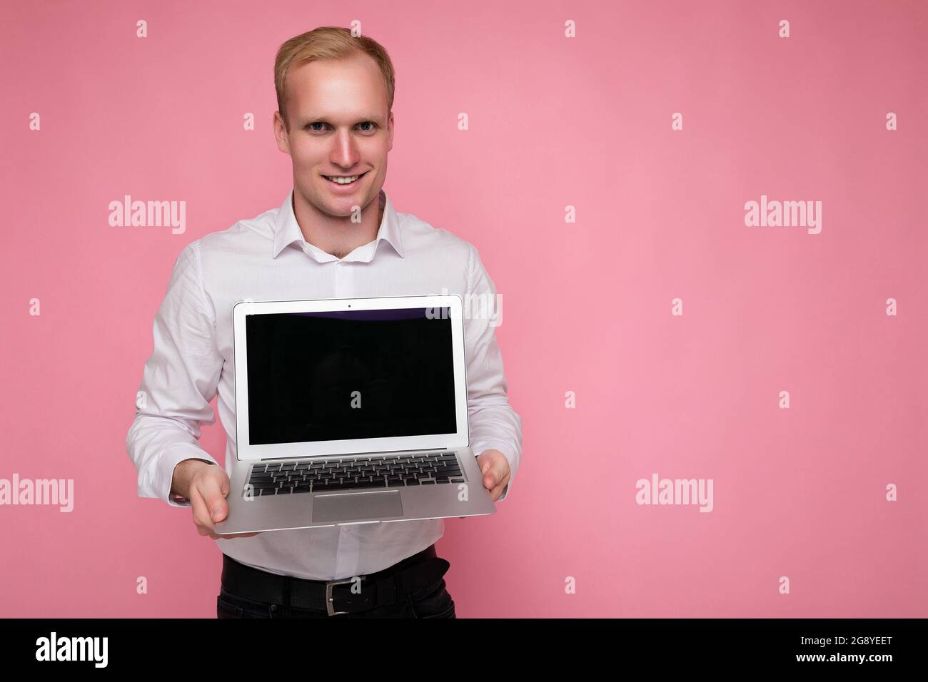 Close-up portrait of handsome blonde man holding computer laptop ...