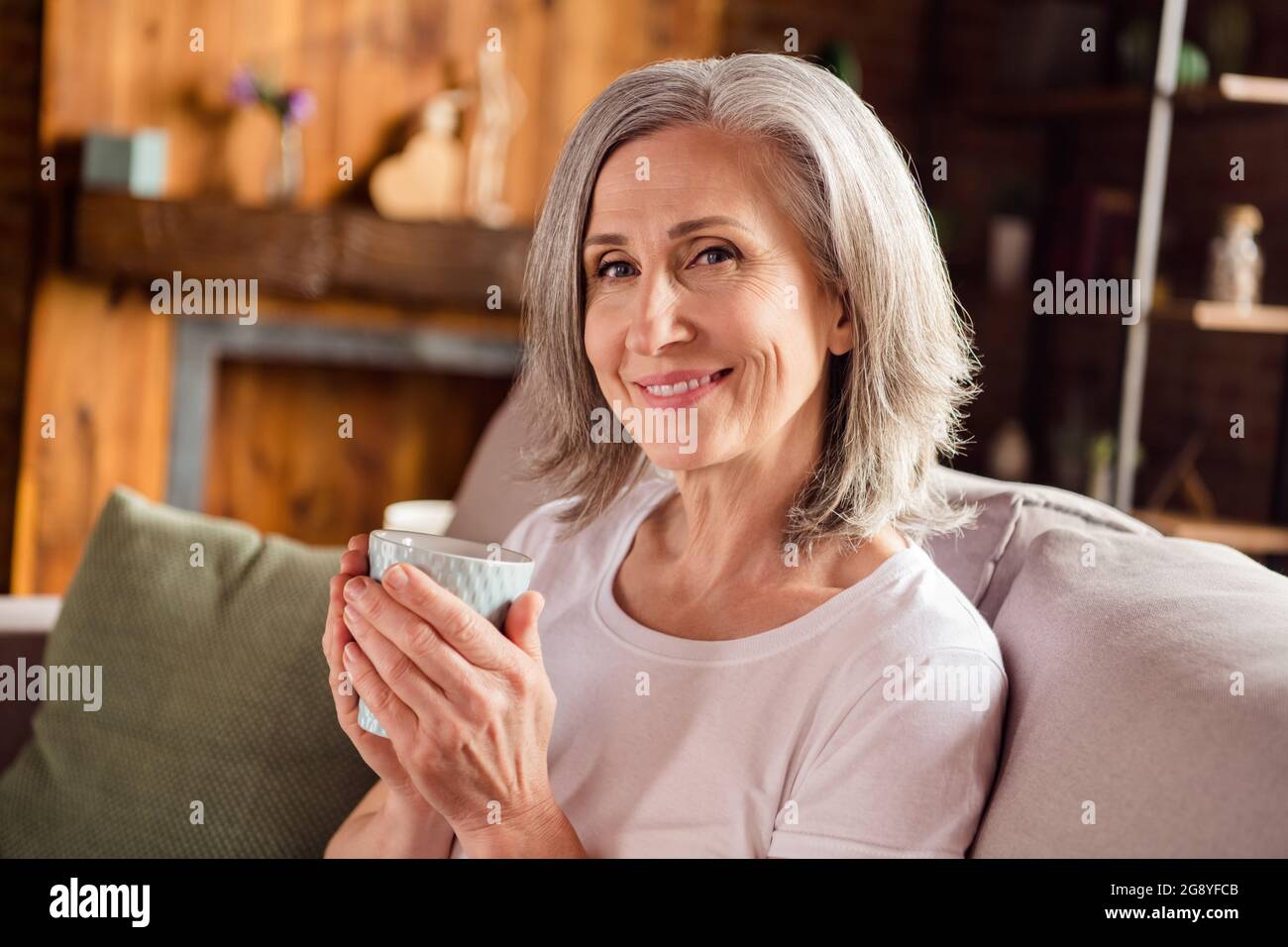 Photo of shiny sweet lady pensioner wear white t-shirt sitting sofa ...