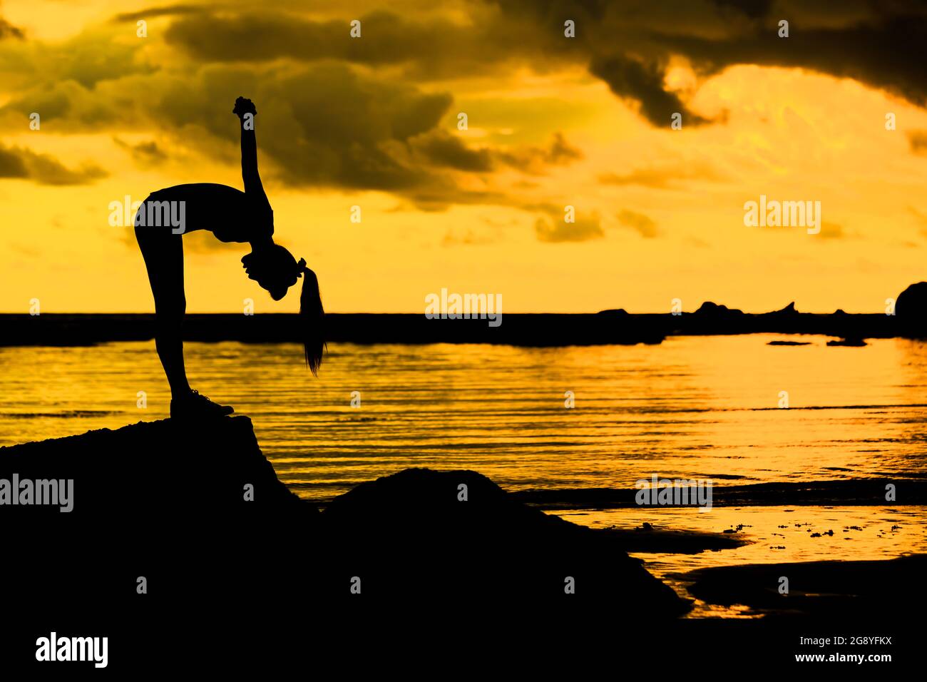 Silhouette scene of Asian woman playing yoga, exercise on rock at ...