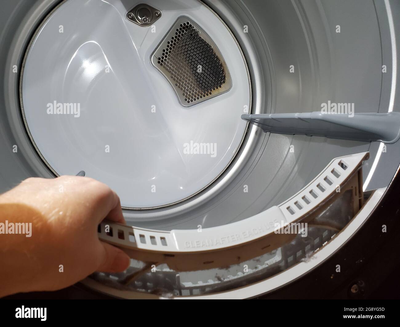 Lighted interior of domestic dryer with air inlet and drum visible ...
