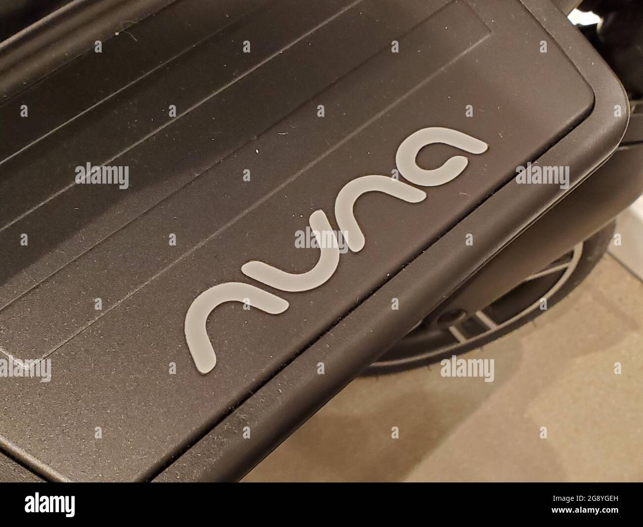 Close-up of a Nuna logo on a black plastic stroller component ...