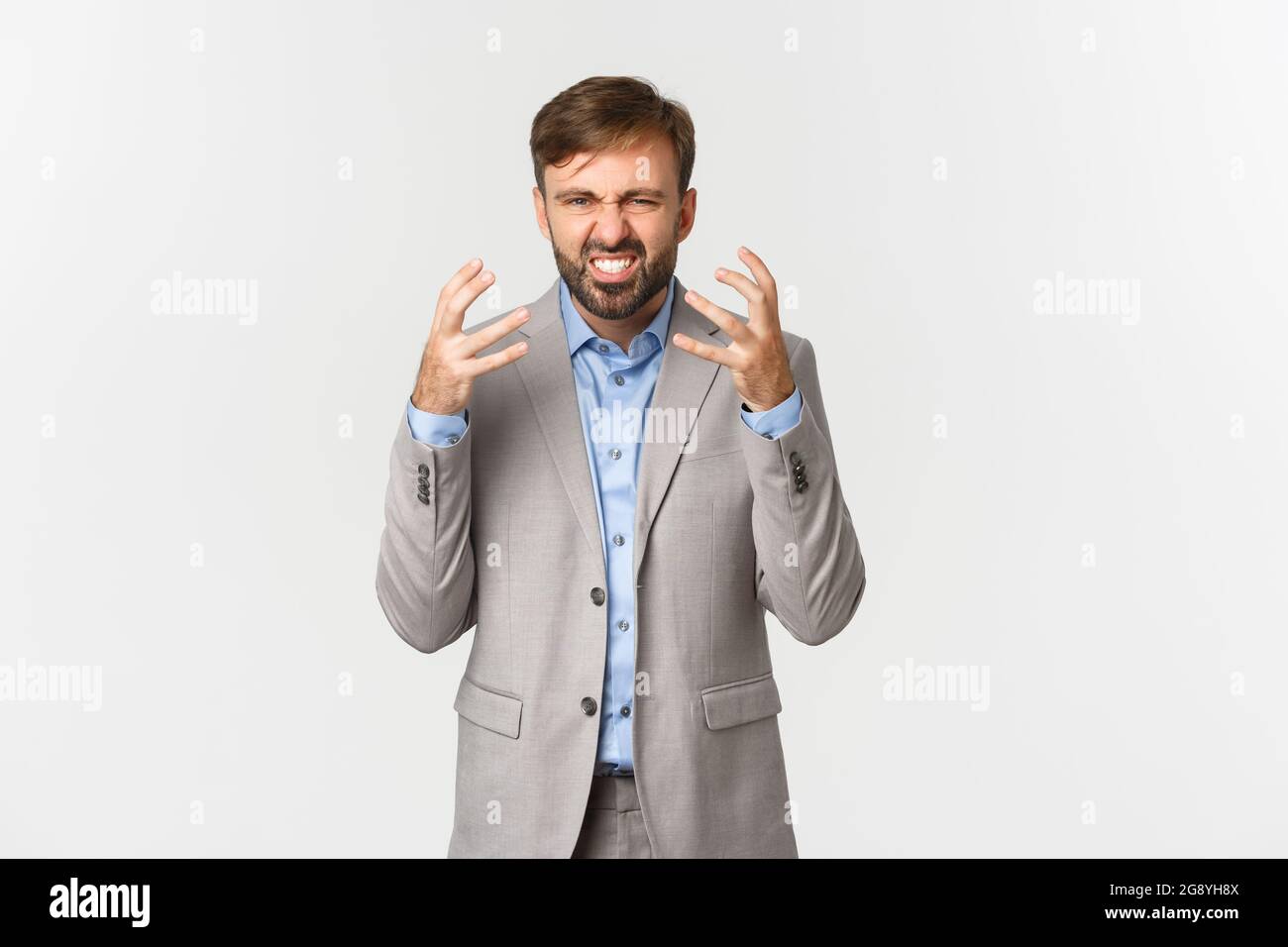 Portrait of bearded male employee in grey suit, complaining and shaking ...