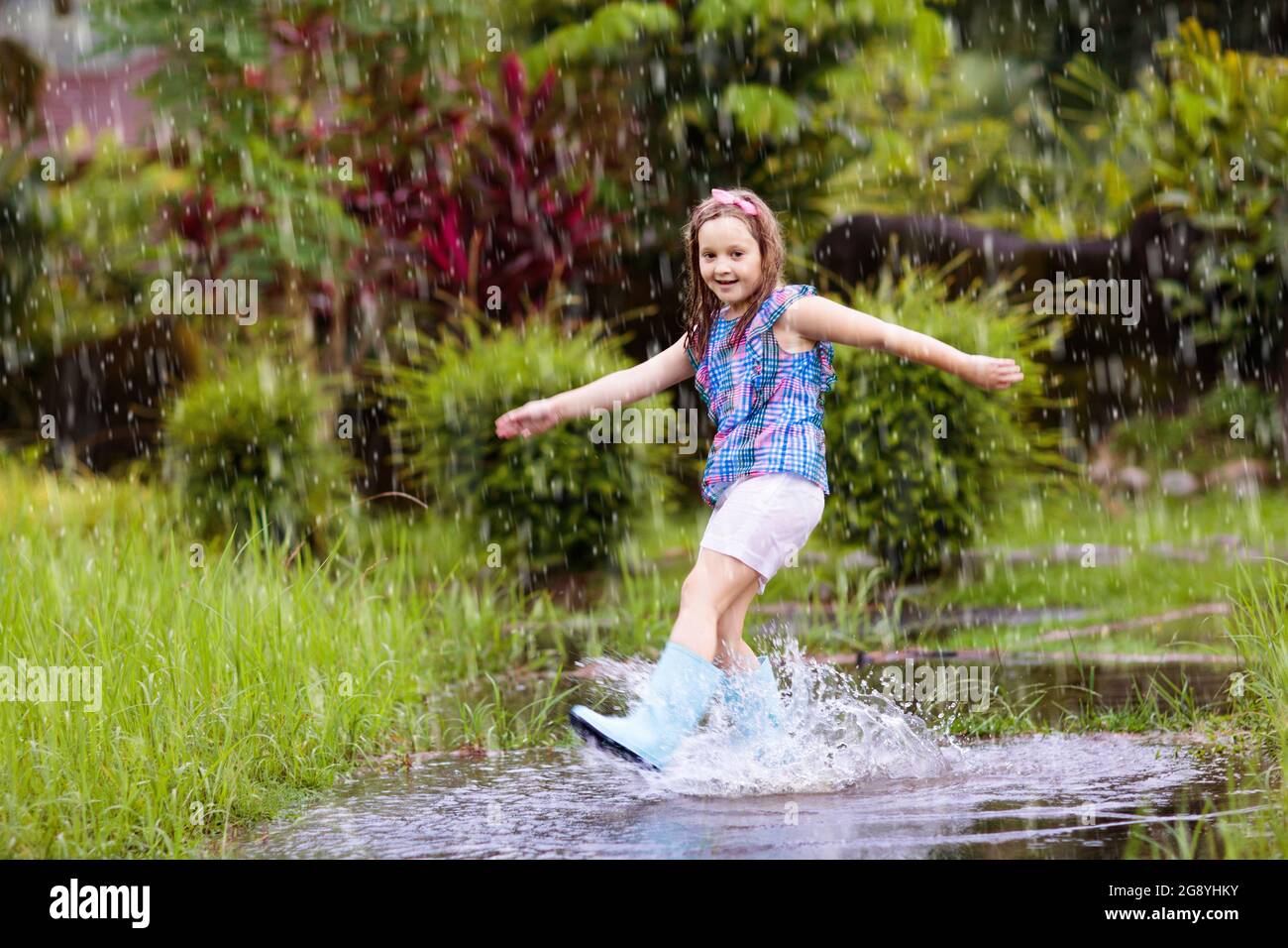 Kid playing out in the rain. Children with umbrella and rain boots play ...