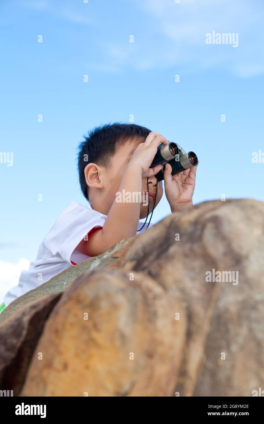 Happy little asian boy exploring outdoors prone on a boulder with ...
