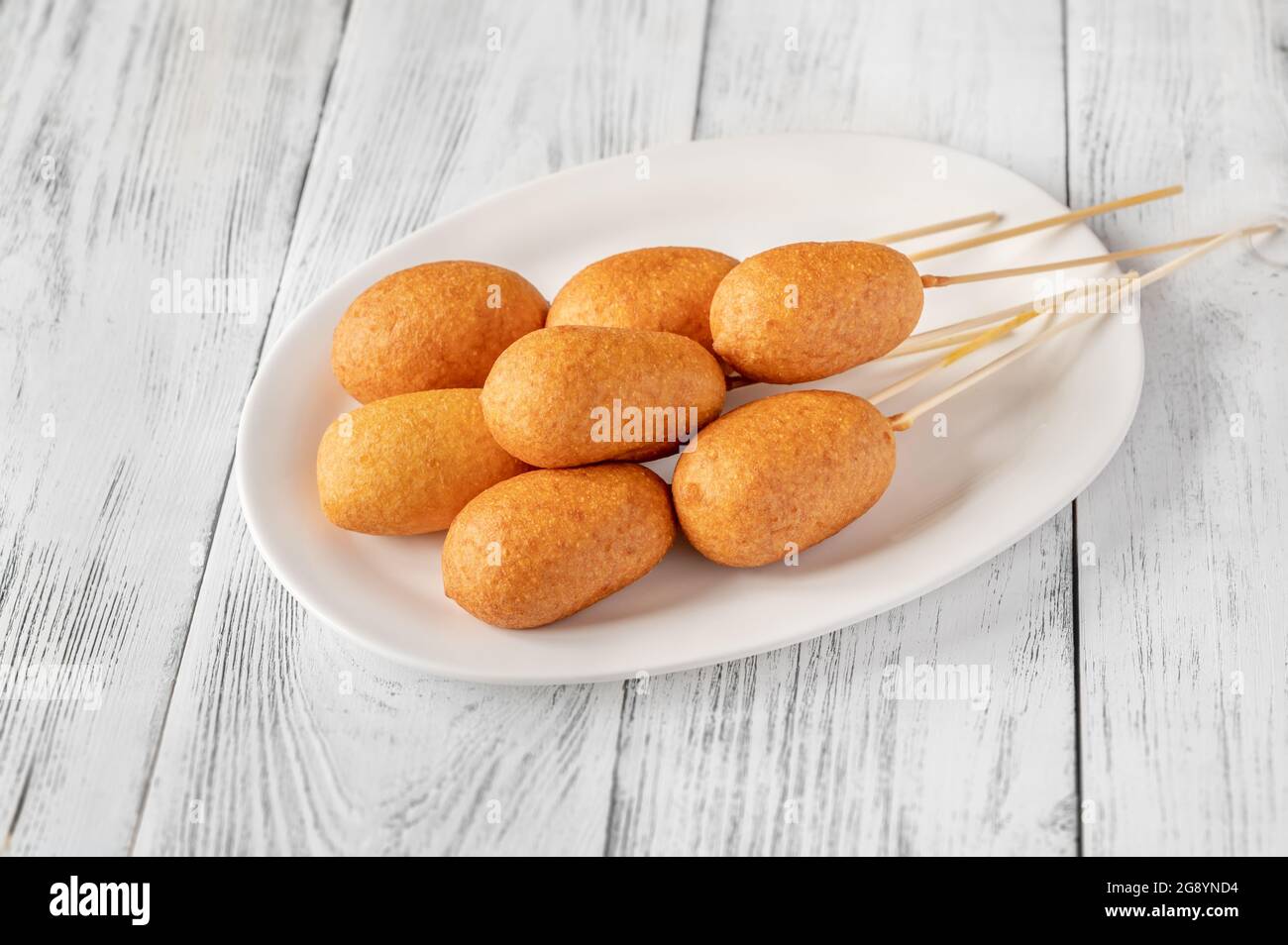 Bunch of mini corn dogs on white serving plate Stock Photo - Alamy
