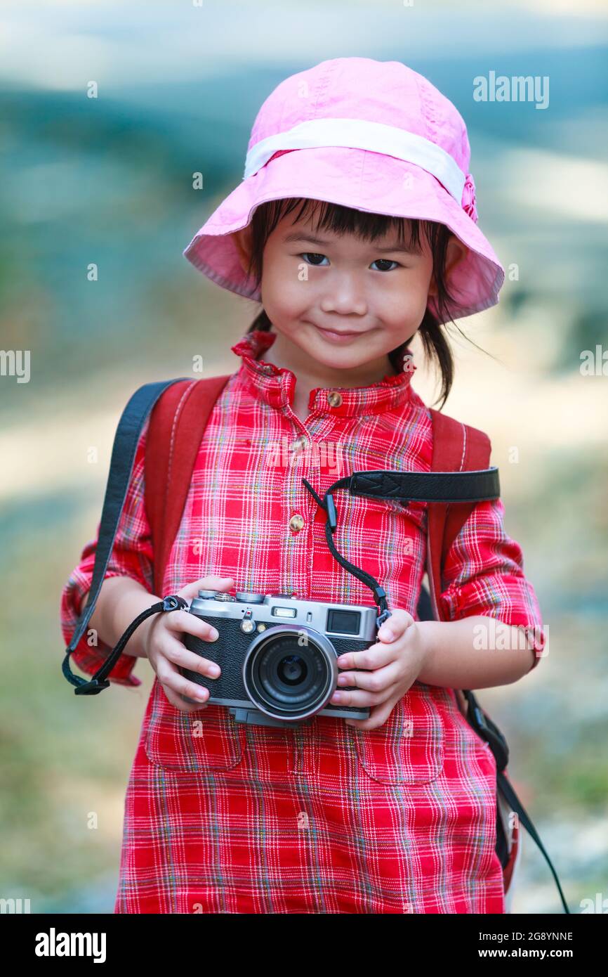 Cute little asian girl with professional digital camera looking at ...