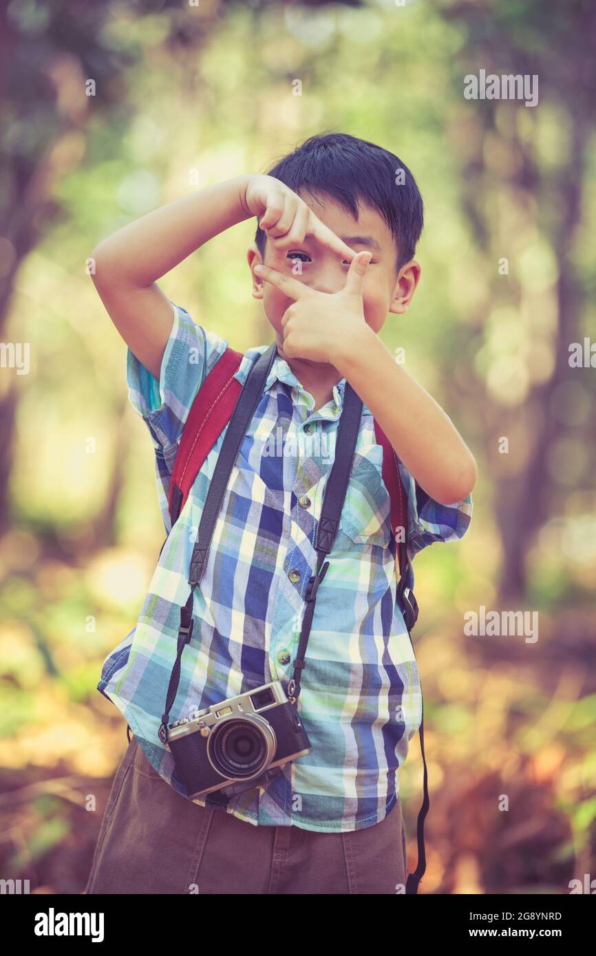 Asian boy with professional digital camera on blurred nature background ...