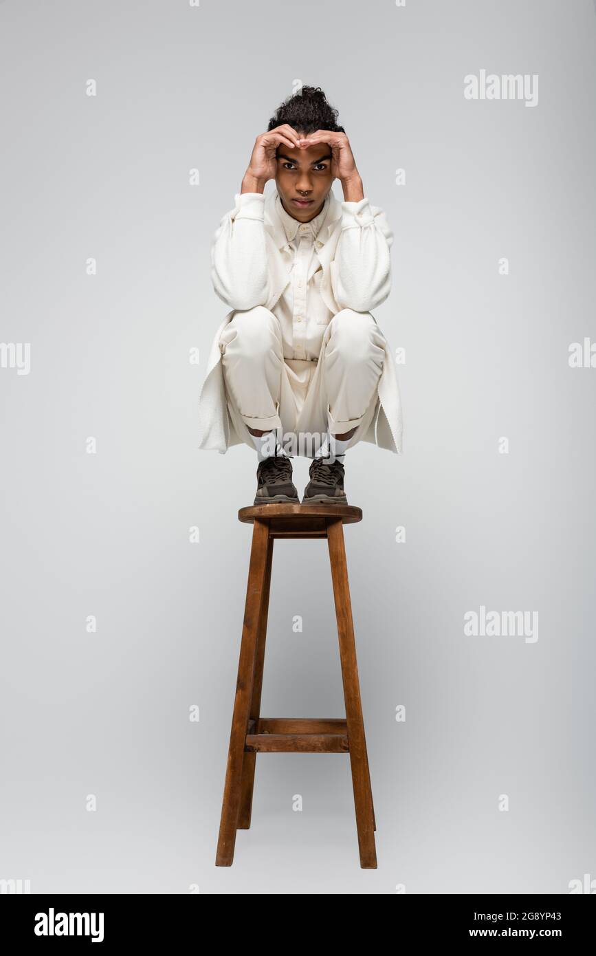 stylish african american man in white suit and sneakers posing on high ...