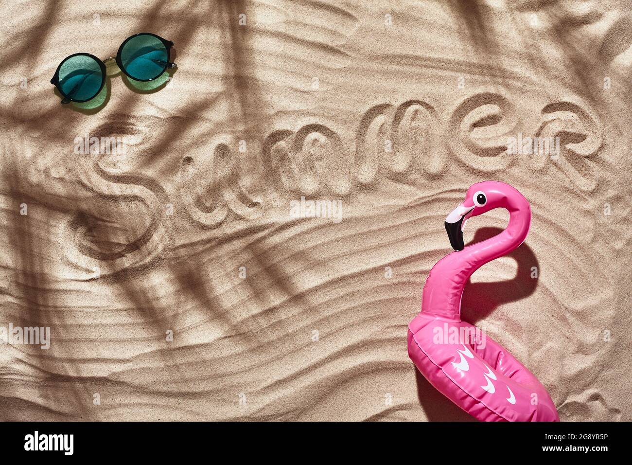 Traveler vacation accessories are laid out on a white beach sand. Flat ...