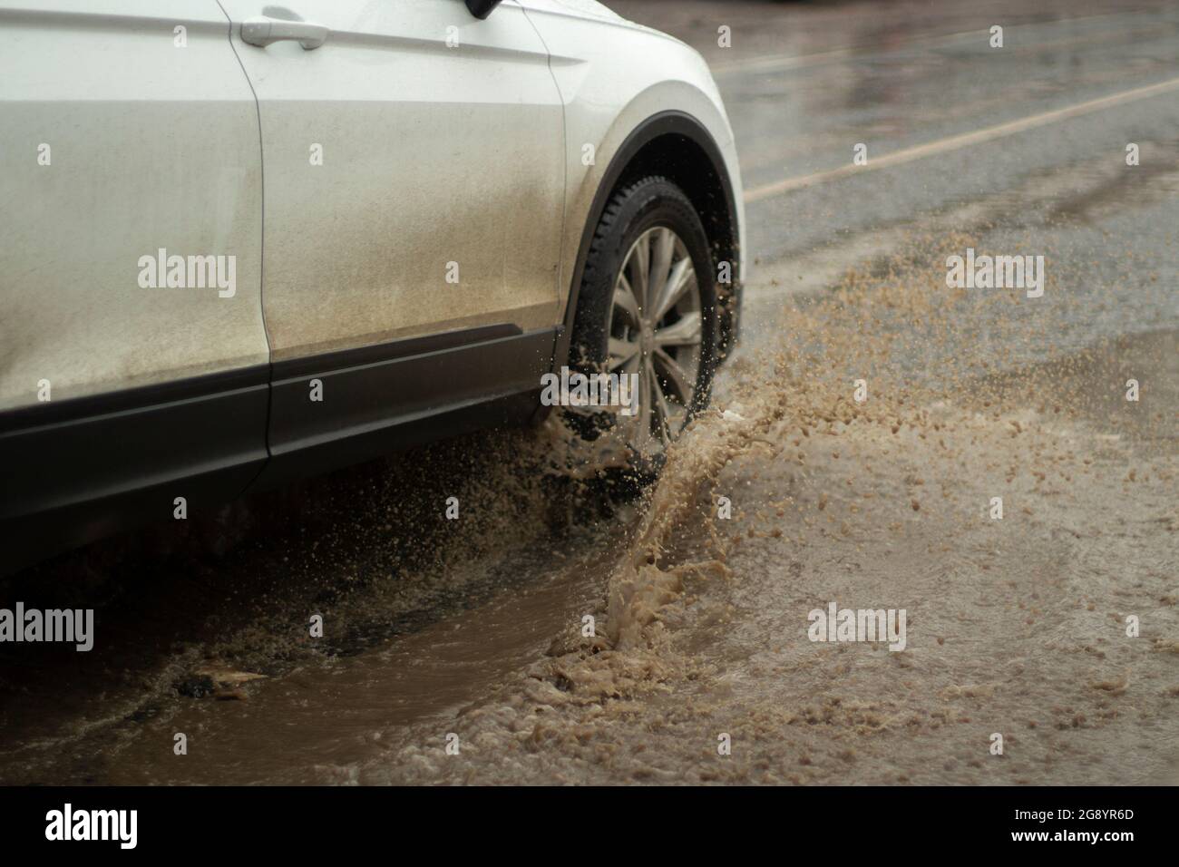 The car is driving in a puddle. White car in the mud. Roads for ...