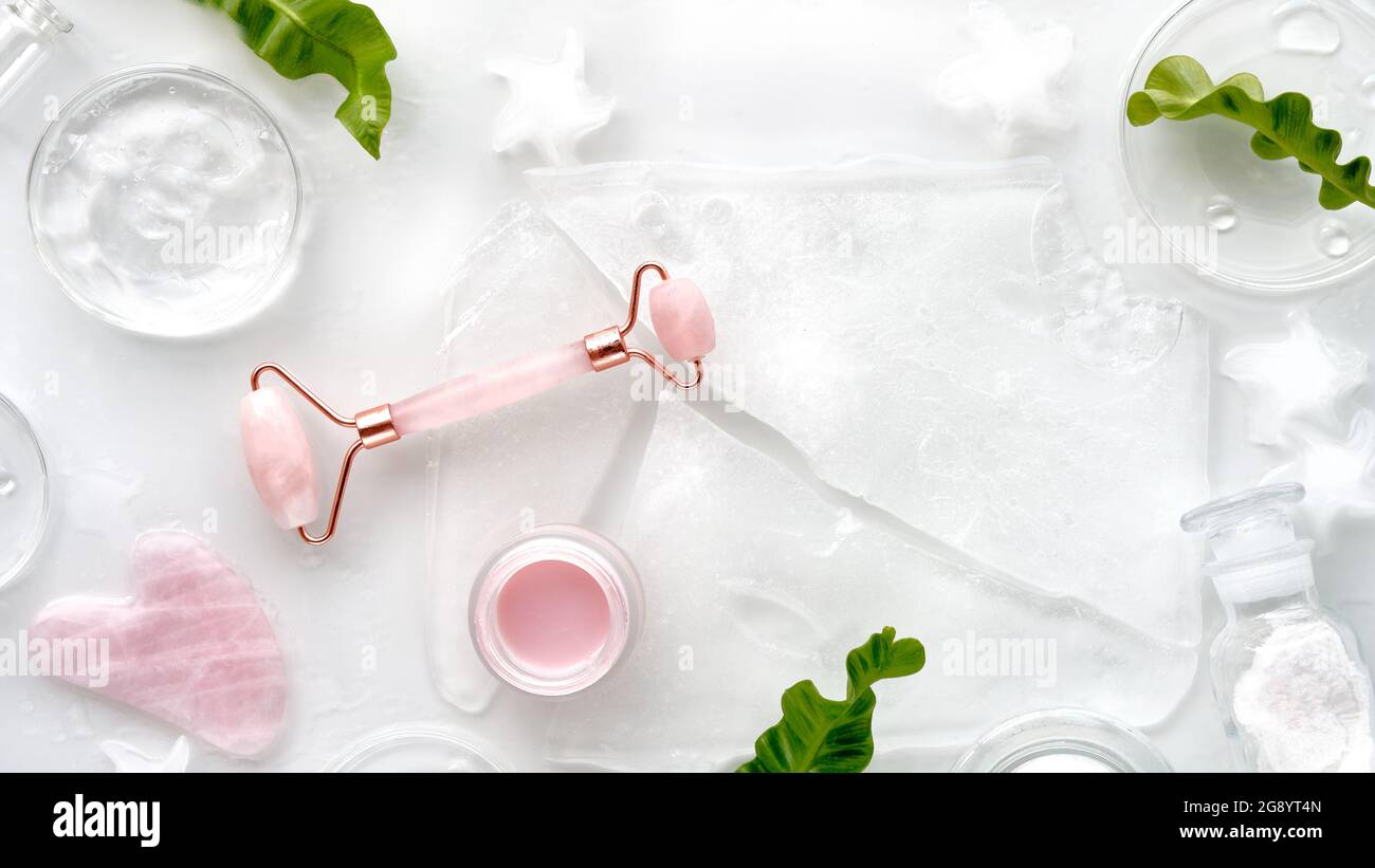 Pink quarts face roller, gua sha stone, pink cream in glass jar. Off ...
