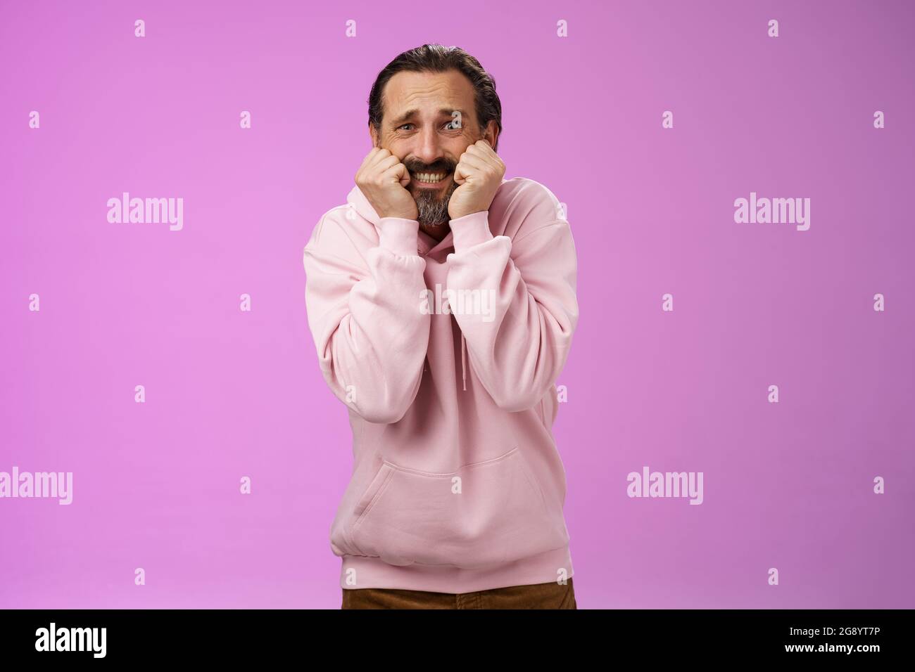 Scared insecure silly adult bearded man grey hair in pink hoodie press ...