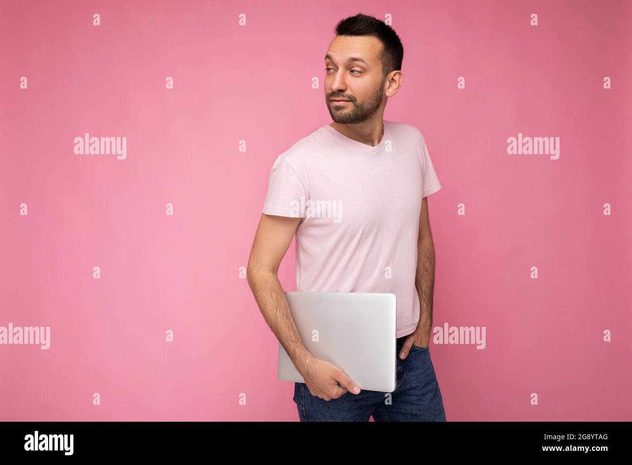 Handsome man holding laptop computer looking at camera in t-shirt on ...