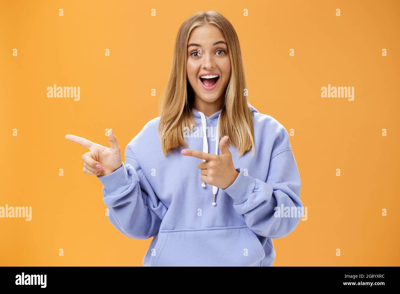 Amused girl pointing at curious copy space showing left with index ...