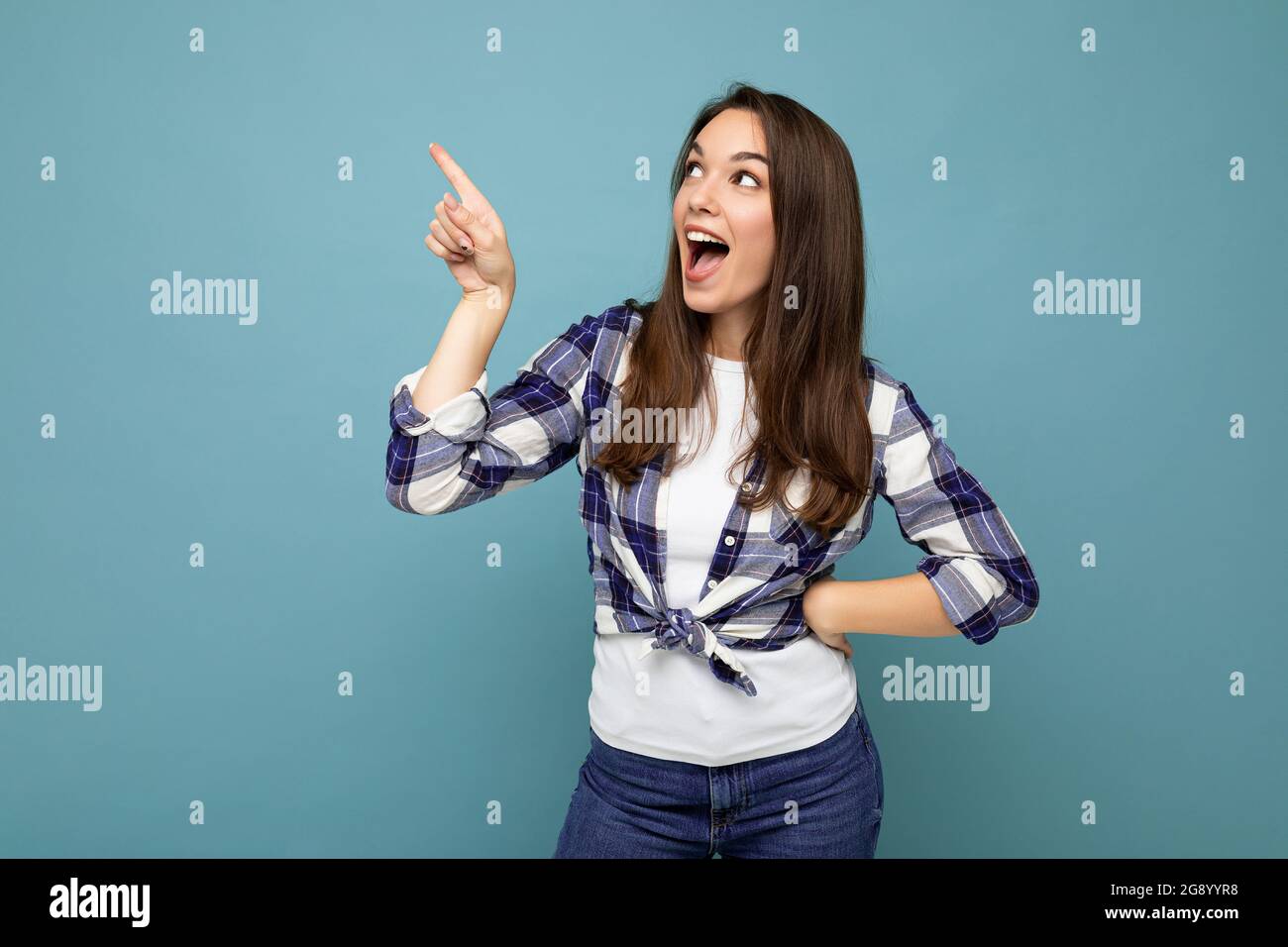 Photo of attractive positive surprised young woman pointing finger up ...