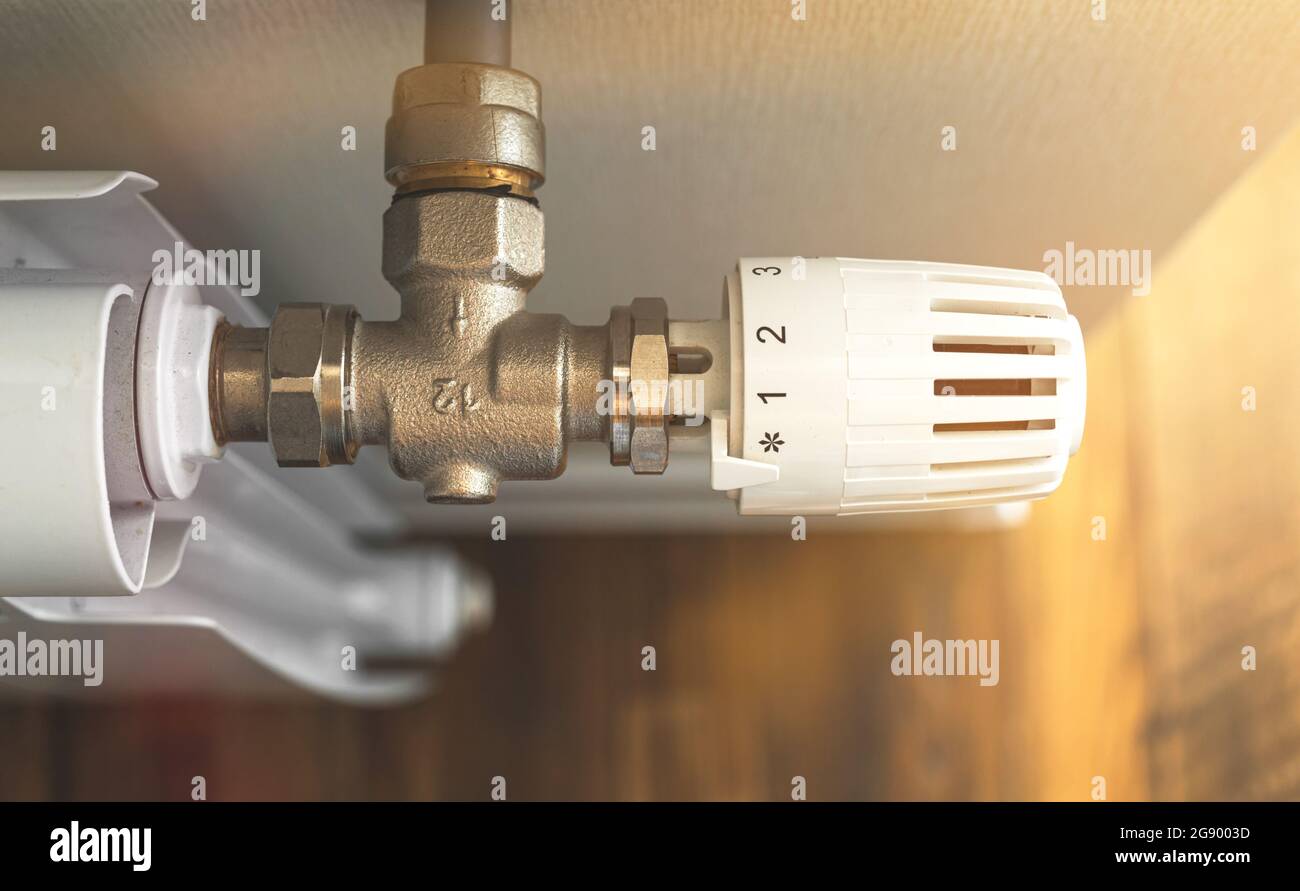 White radiator with thermostat in home, modern interior background ...