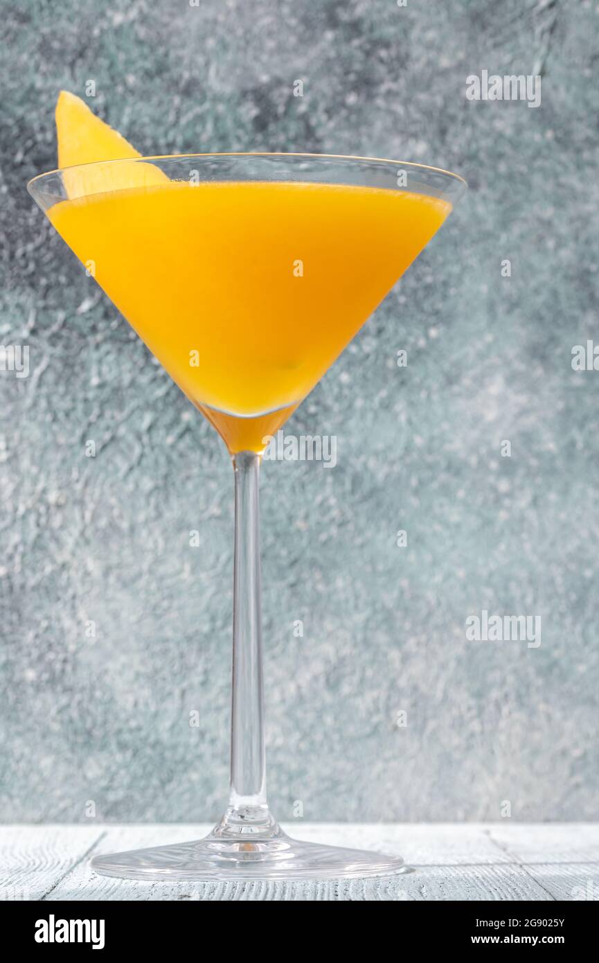 Glass of Apricot Mango Cocktail garnished with slice of fresh mango ...