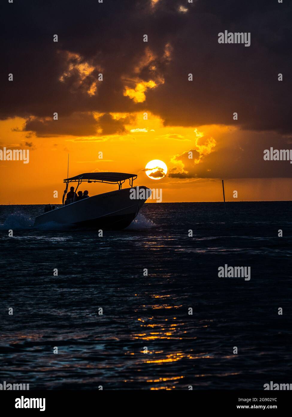 Vertical shot of a boat swimming in the ocean during a sunset ...