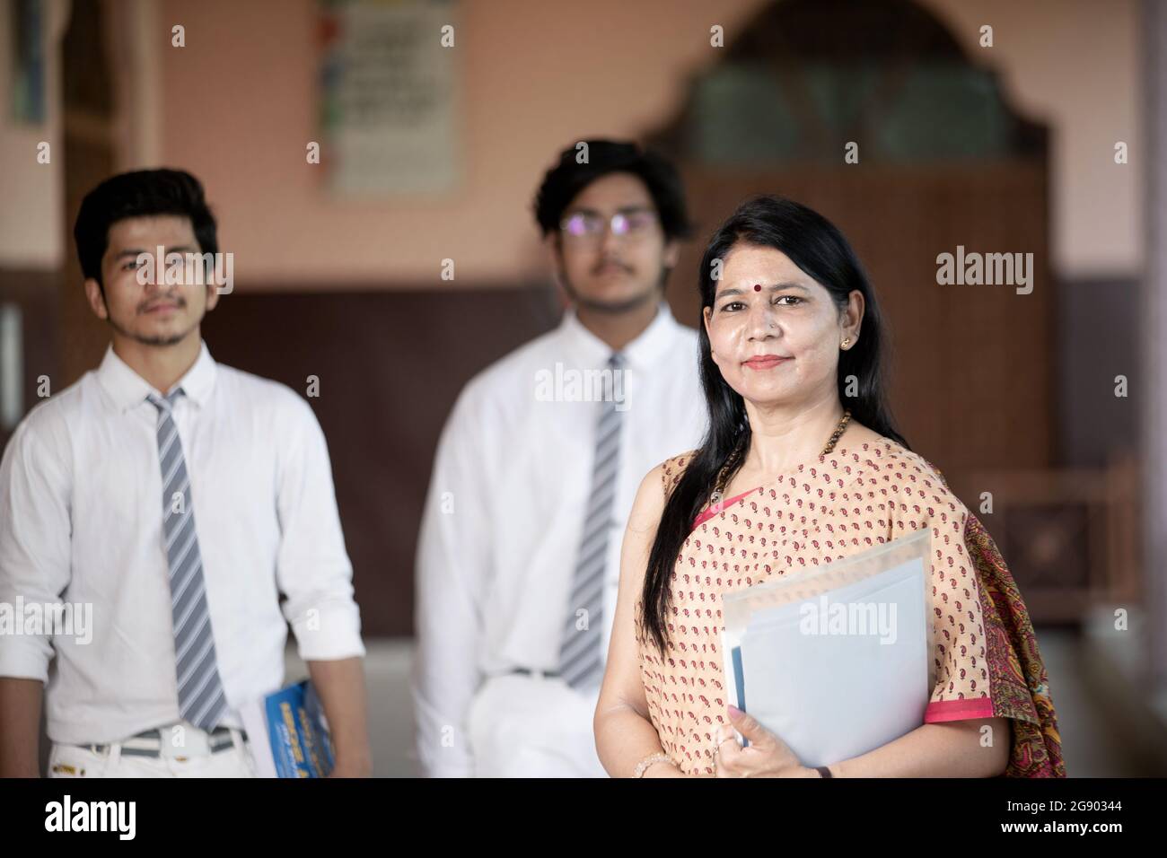 Indian school teacher with students in background Stock Photo - Alamy