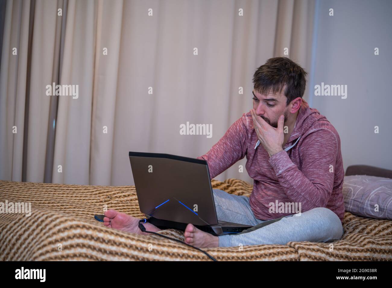 Anxious young Caucasian man working remotely on the computer sitting on ...