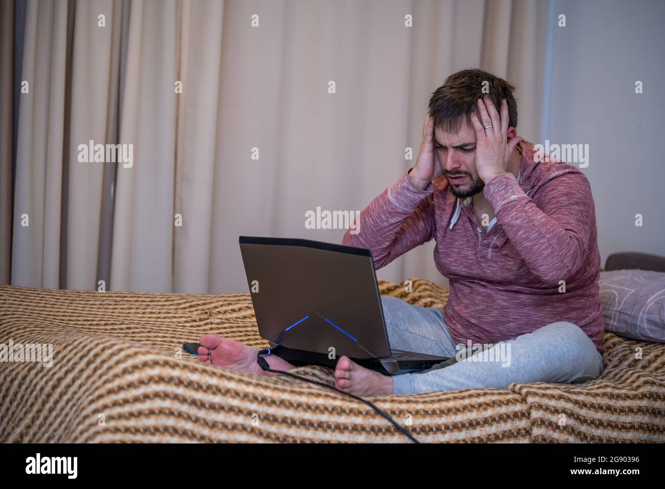 Anxious young Caucasian man working remotely on the computer sitting on ...