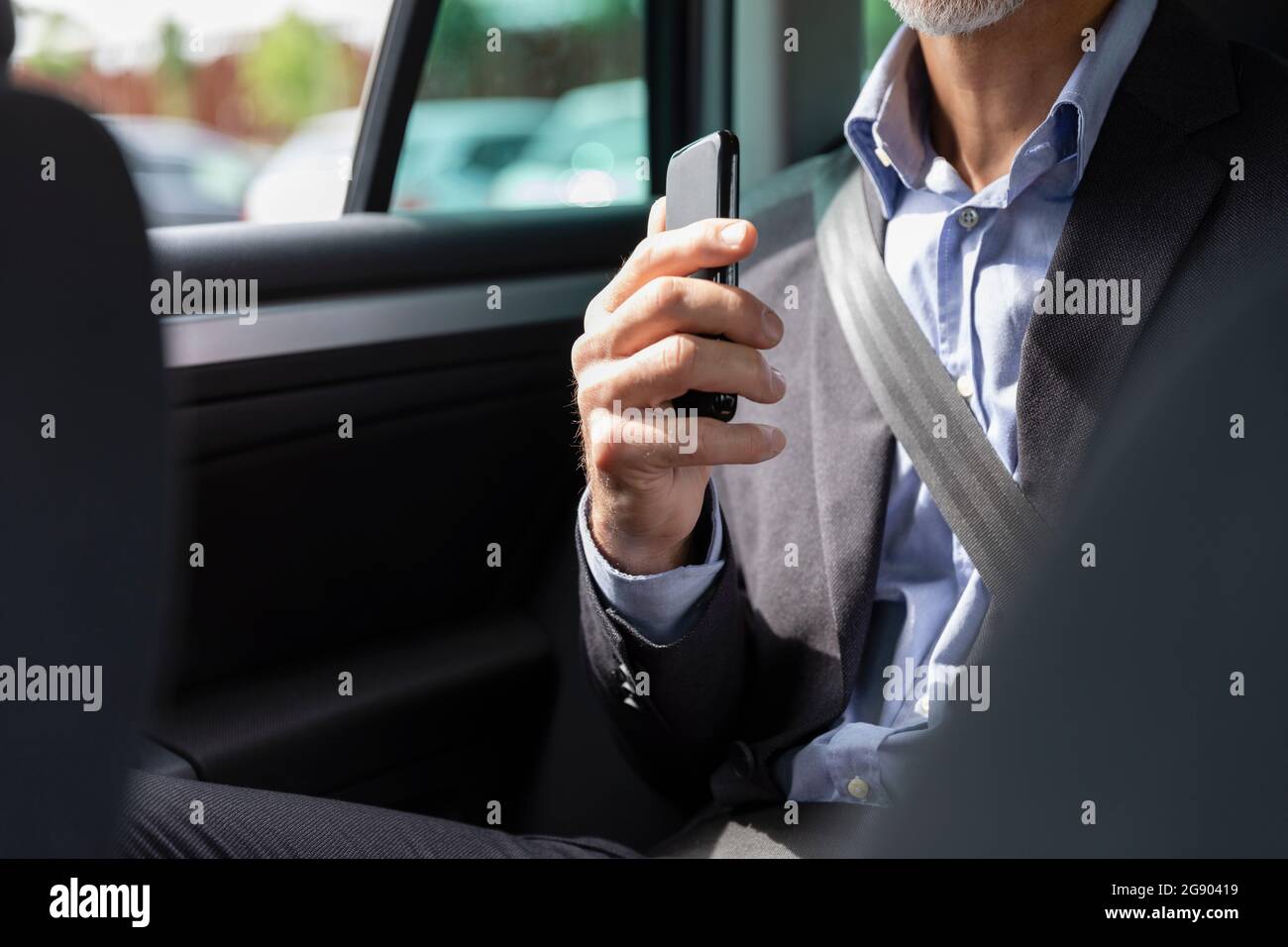 Businessman holding smart phone in car Stock Photo - Alamy