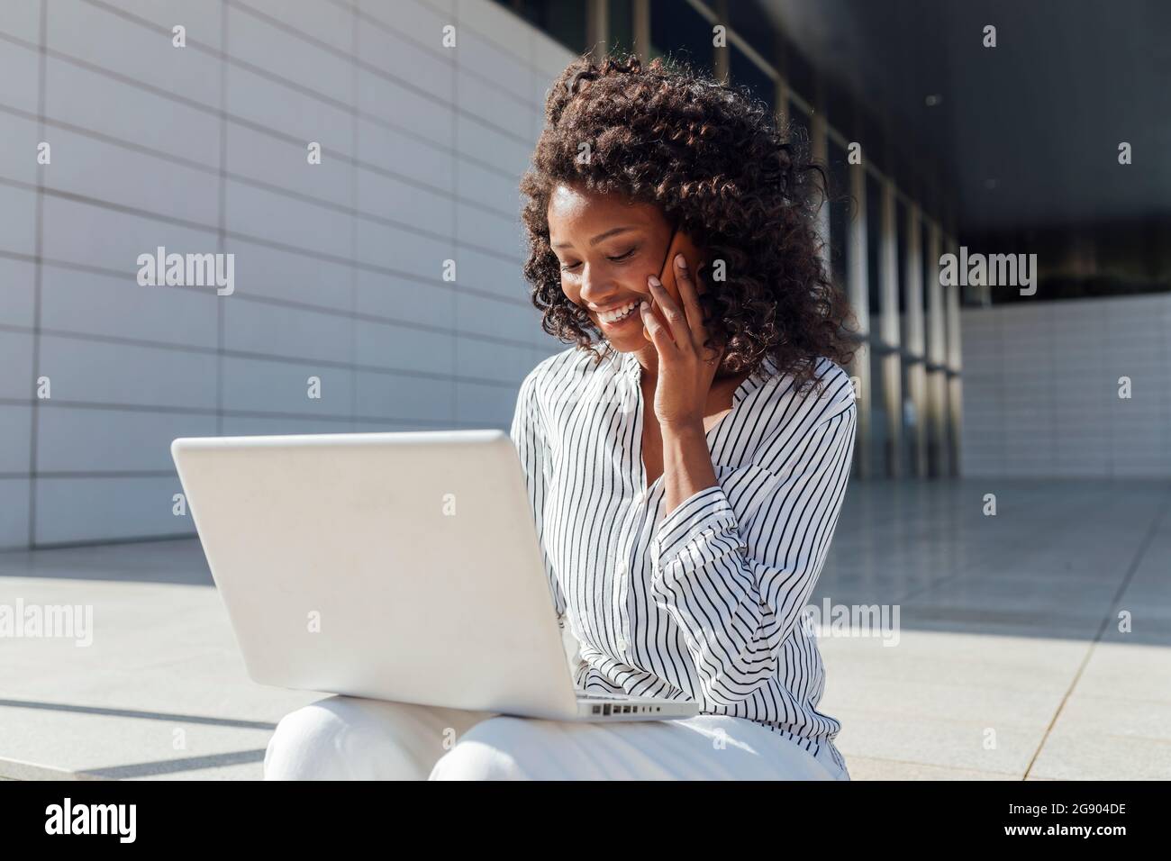 Happy female professional talking on mobile phone while sitting with ...