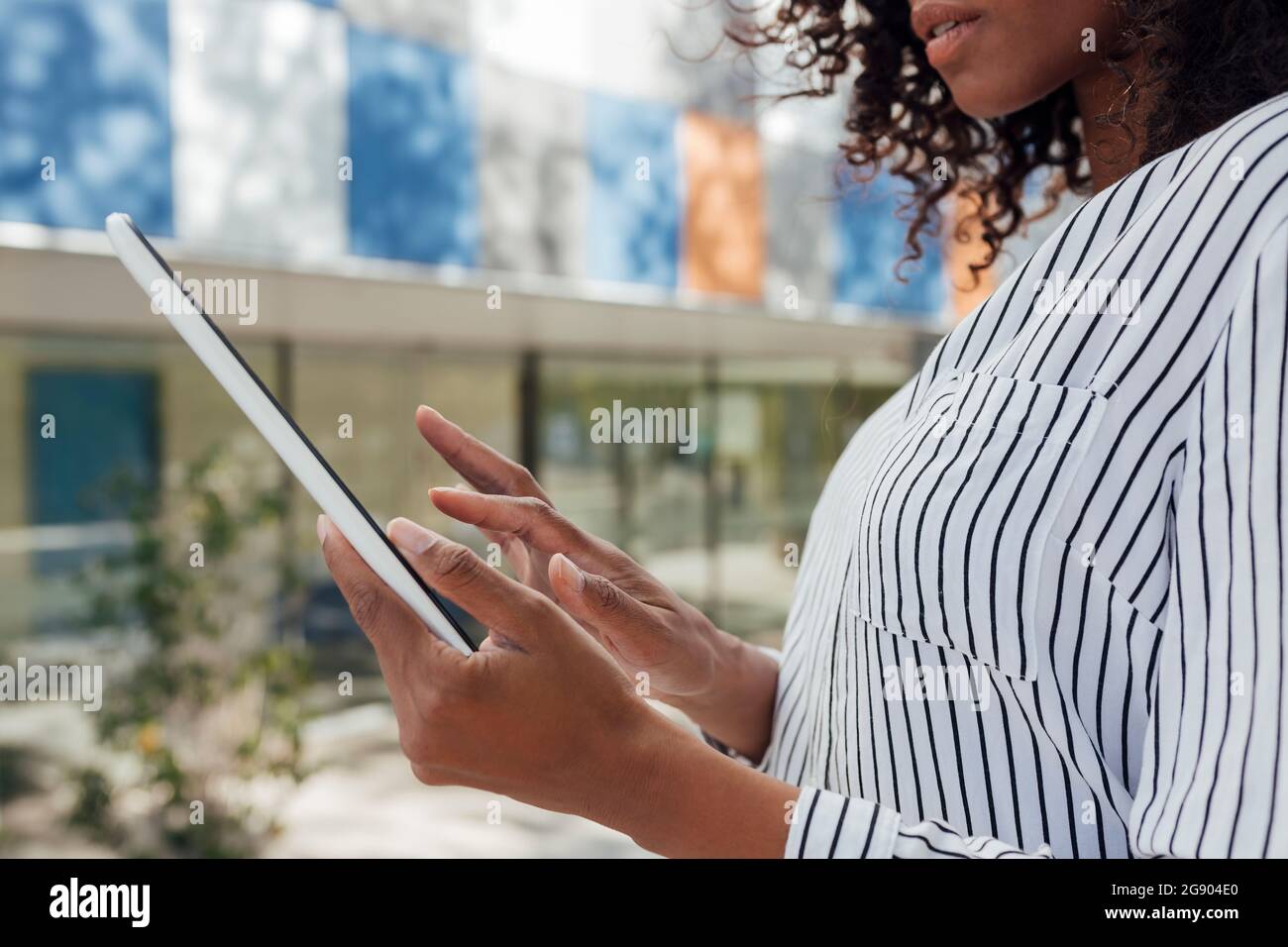 Businesswoman using digital tablet while standing outside office ...