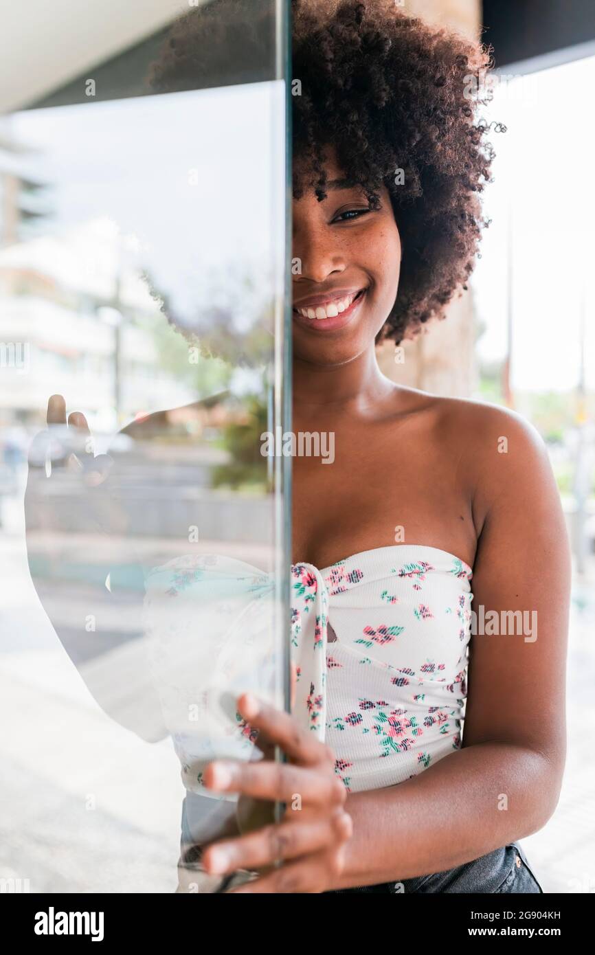 Smiling Afro woman standing behind glass Stock Photo - Alamy