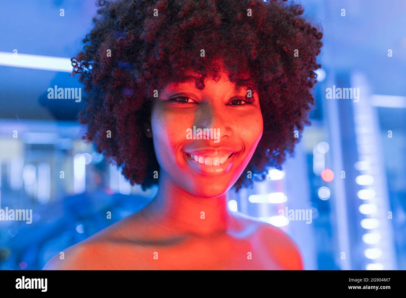 Smiling young woman with neon lights on face Stock Photo - Alamy